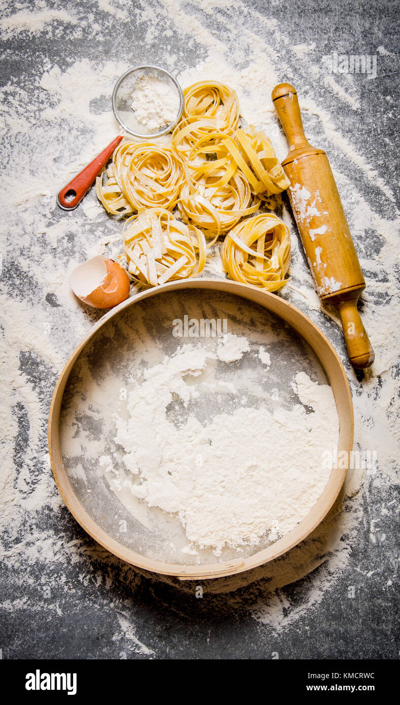 Pasta background. Sift flour and pasta with a rolling pin and eggs. On ...
