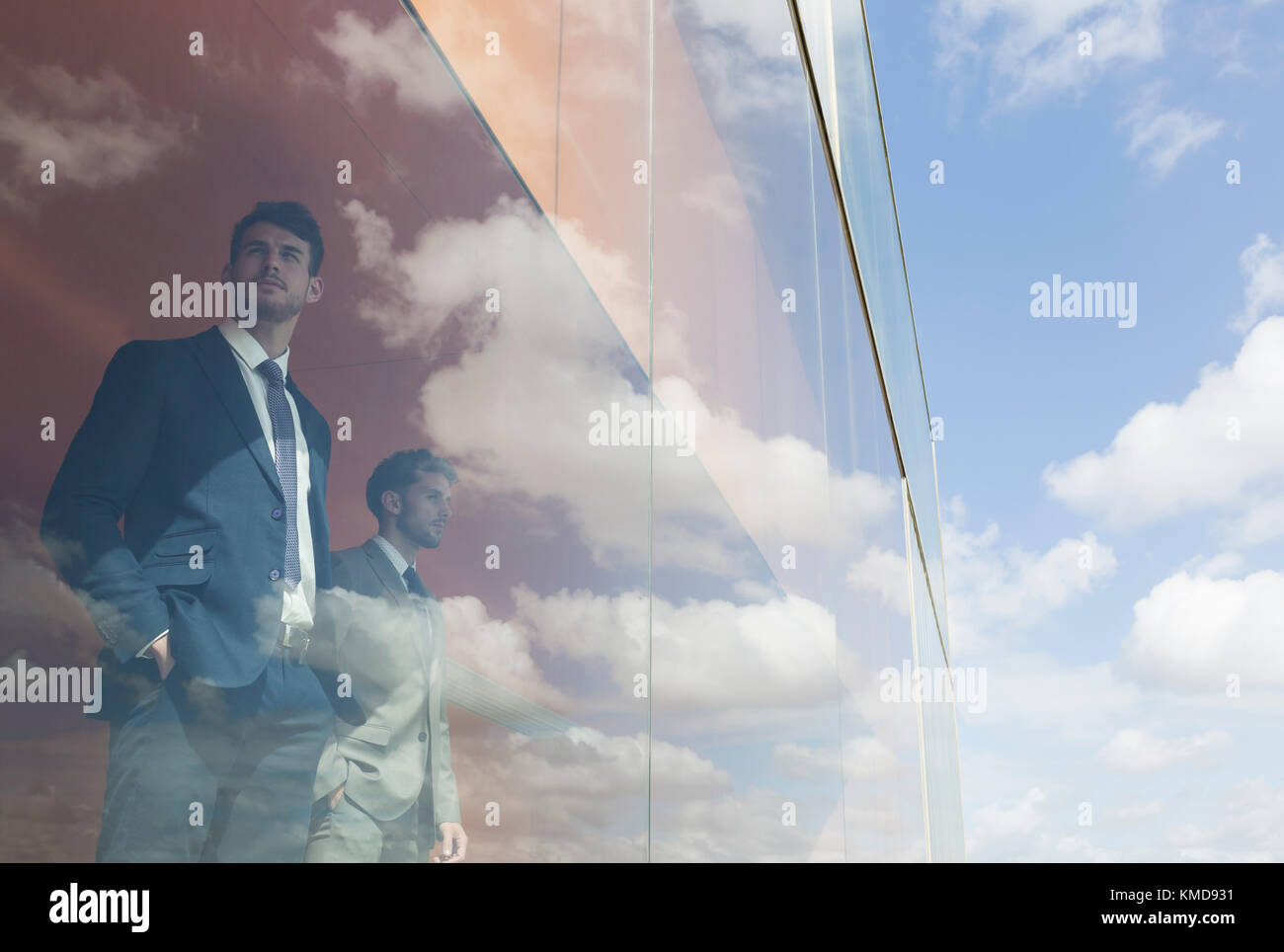 Pensive businessmen looking out modern office window at sunny blue sky ...