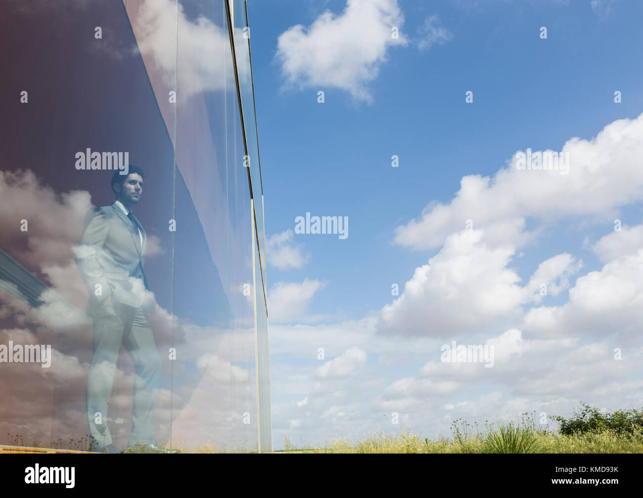 Pensive businessman looking out modern office window at sunny blue sky ...