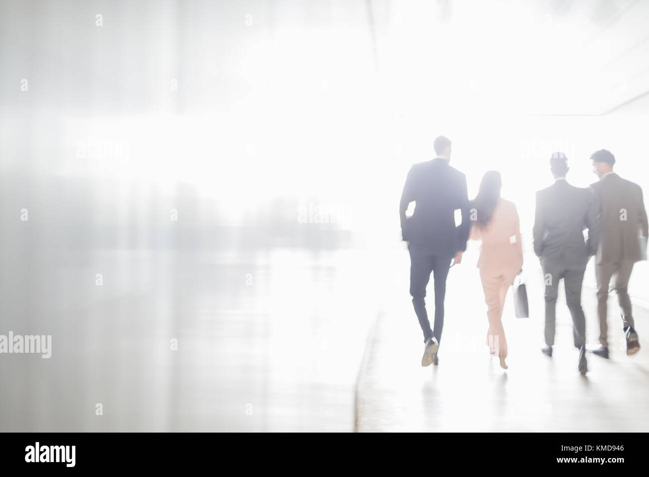 Business people walking in sunny office corridor Stock Photo - Alamy
