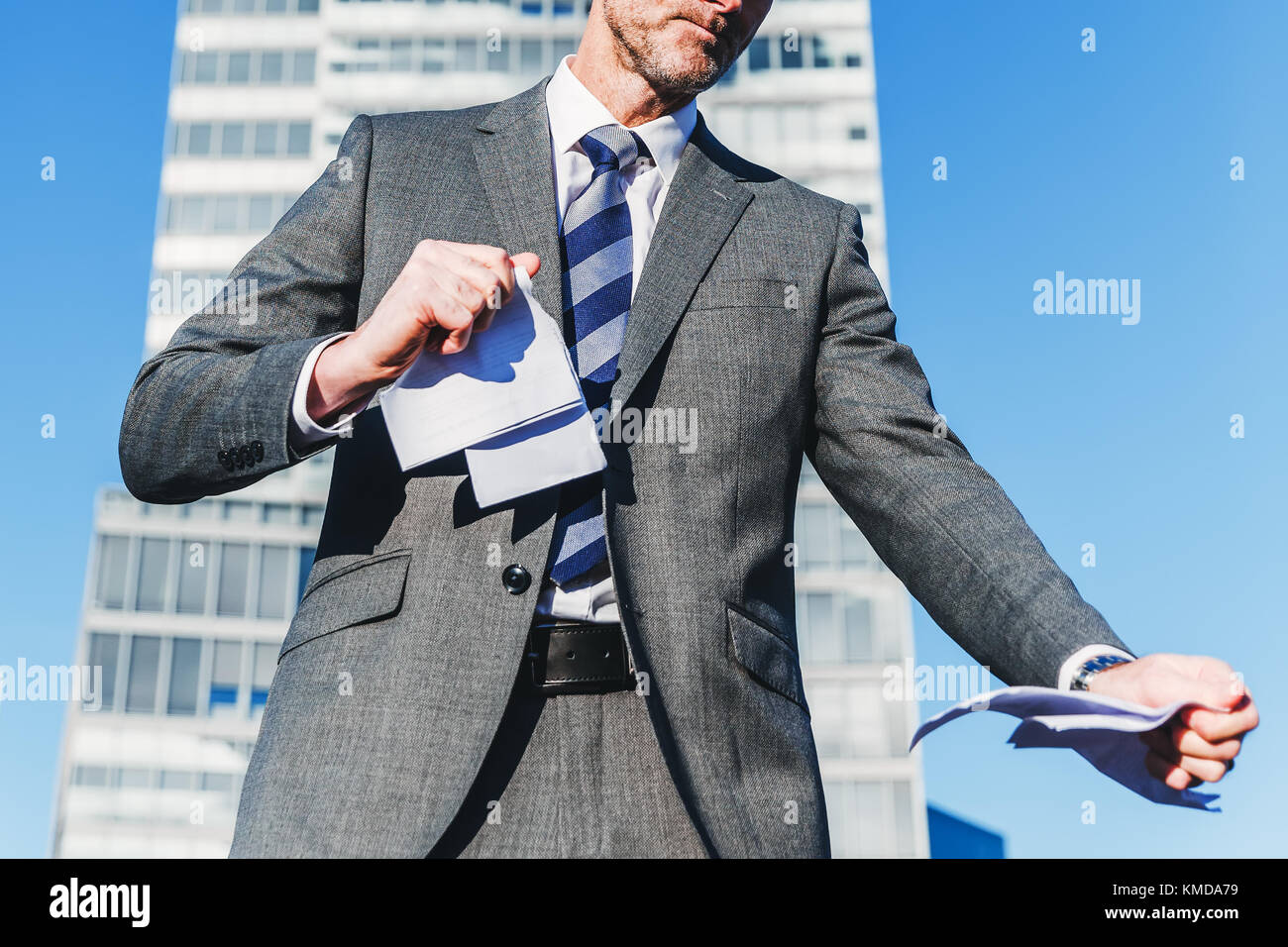 angry businessman stands in front of a skyscraper and rips documents in ...