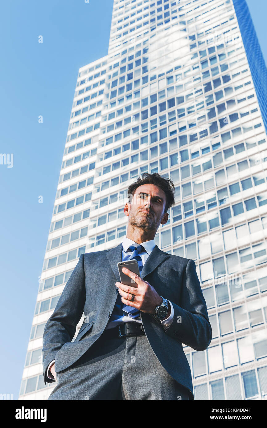 portrait of a businessman who stands in front of a skyscraper and ...