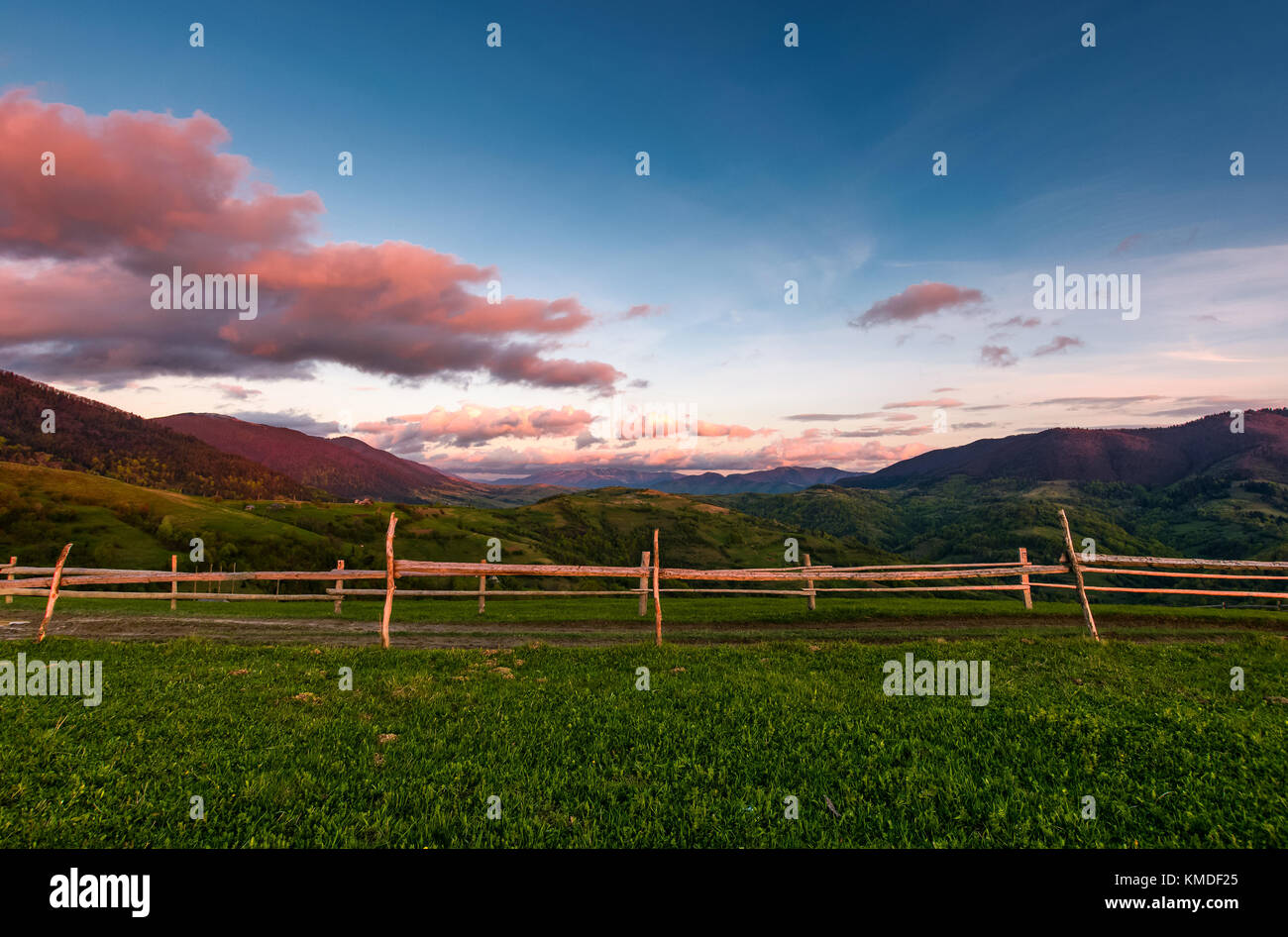wooden fence on a grassy hill at sunset. beautiful rural scenery with ...