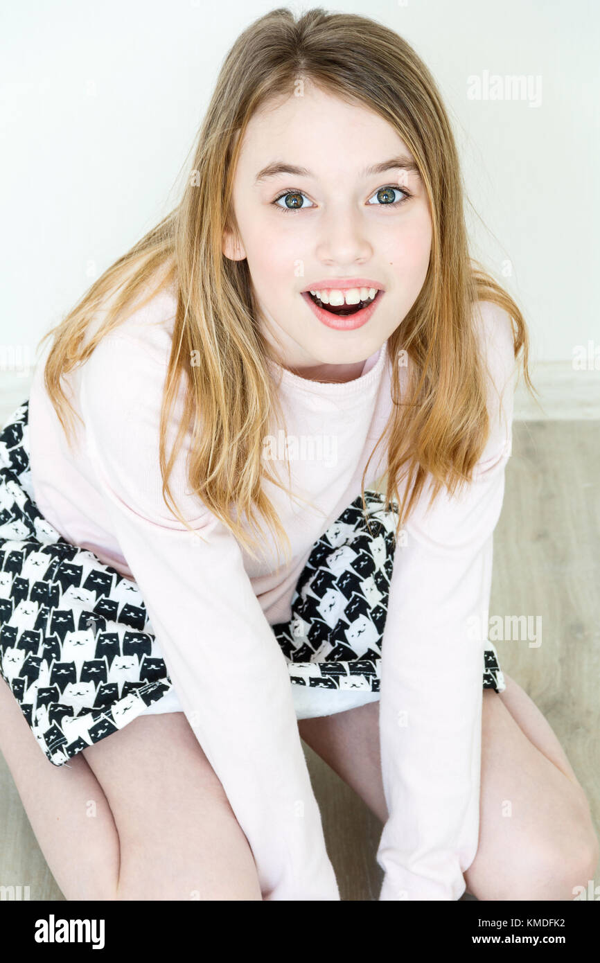 Laughing cute girl eleven years old sitting on floor Stock Photo - Alamy