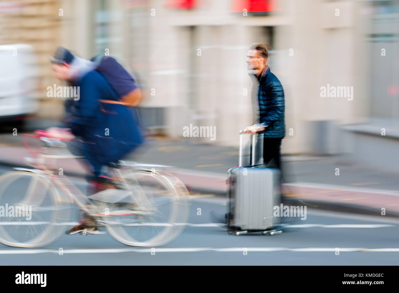 motion blur picture of a businessman with trolley bag who crosses the ...