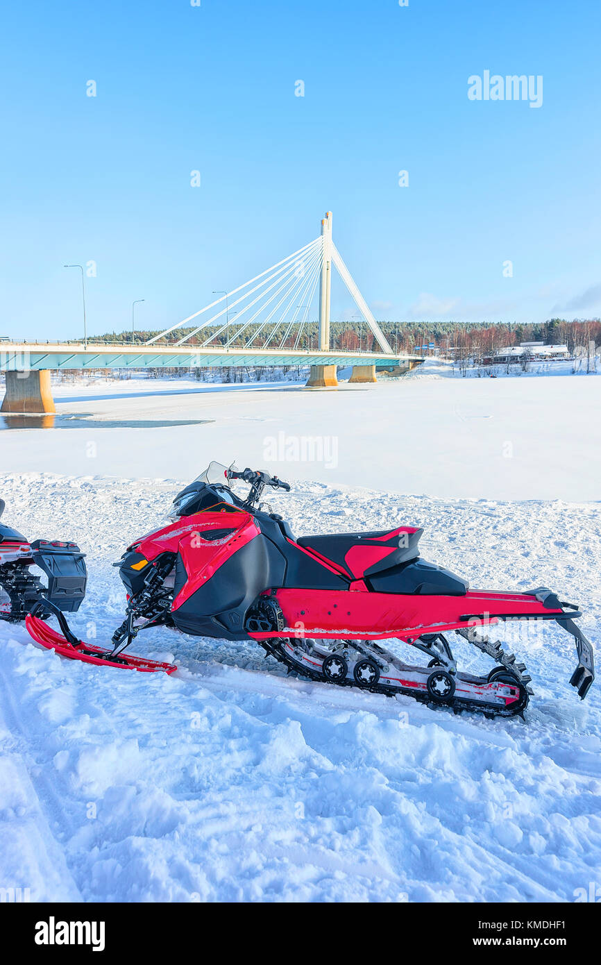 Red snowmobile in frozen lake at Candle bridge in winter Rovaniemi ...