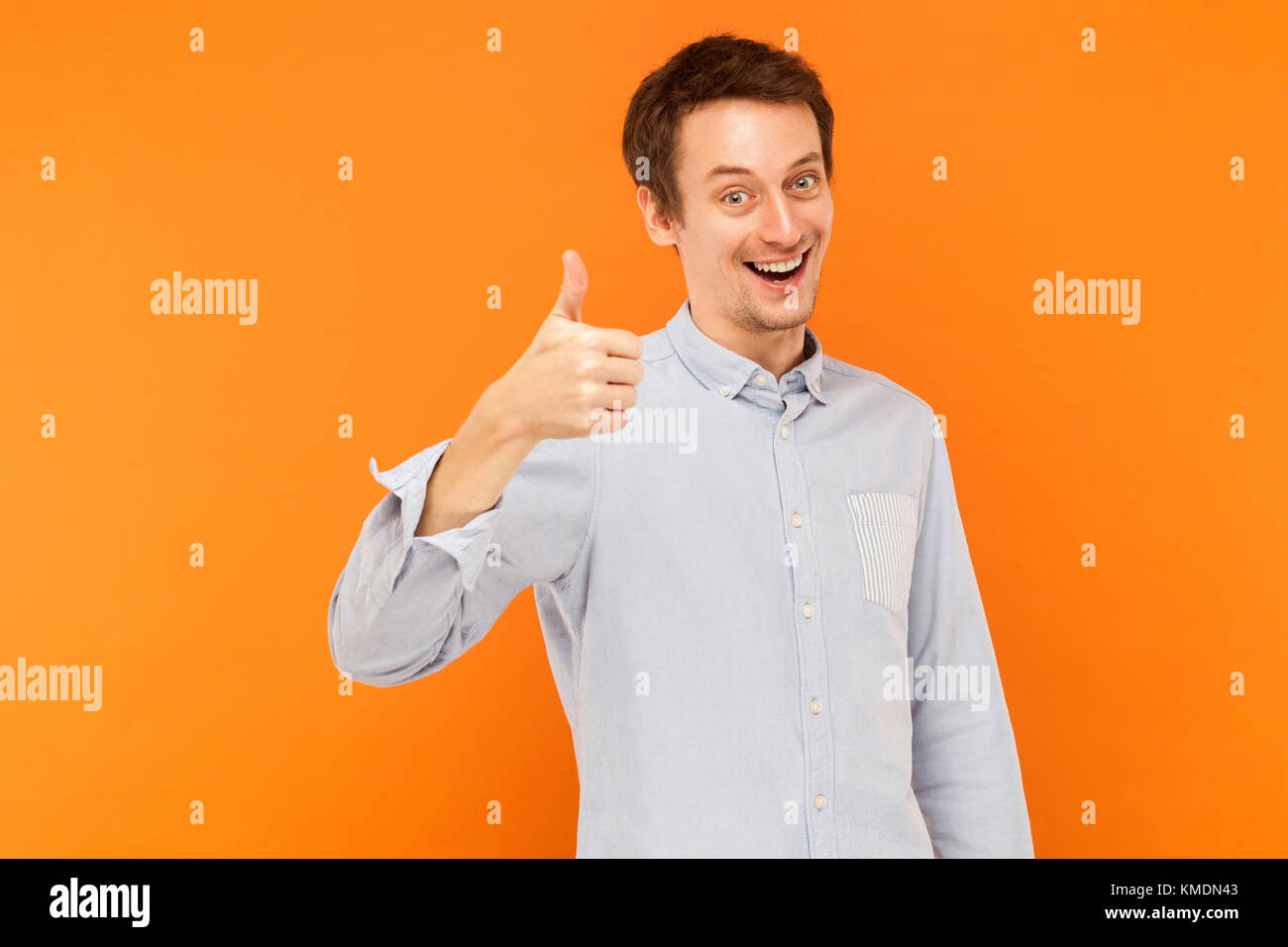 Like sign. Smiling man thumbs up and looking at camera. Orange wall ...