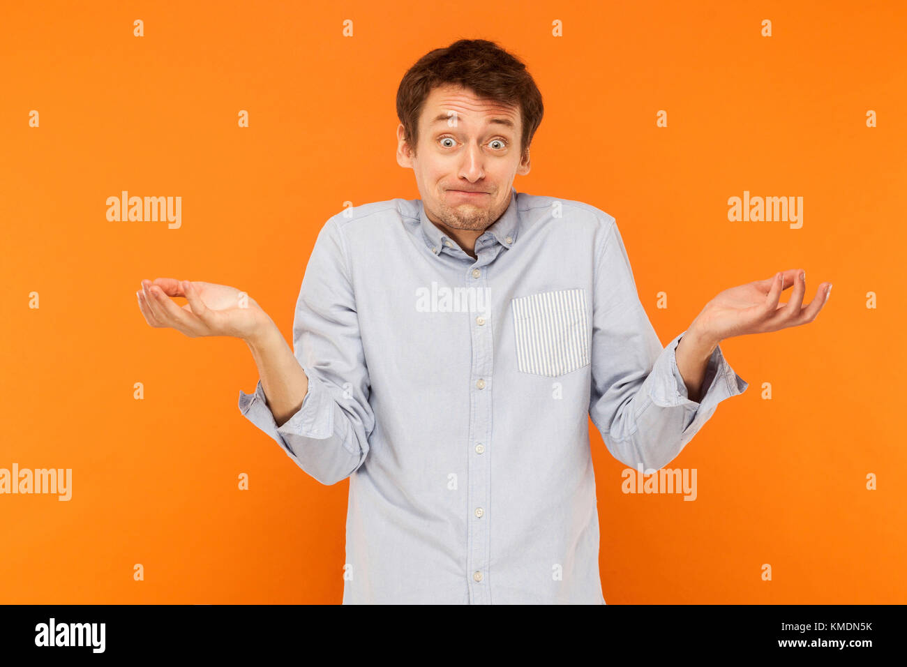 Who know's. Confused man looking at camera. Studio shot, orange ...