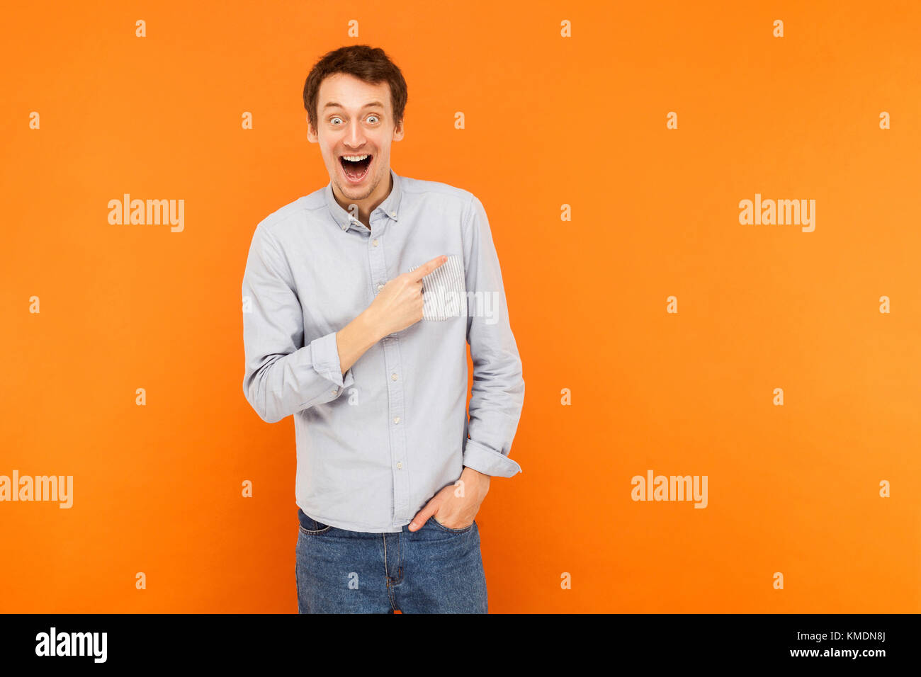 Shocked man pointing finger at copy space. Studio shot, orange ...