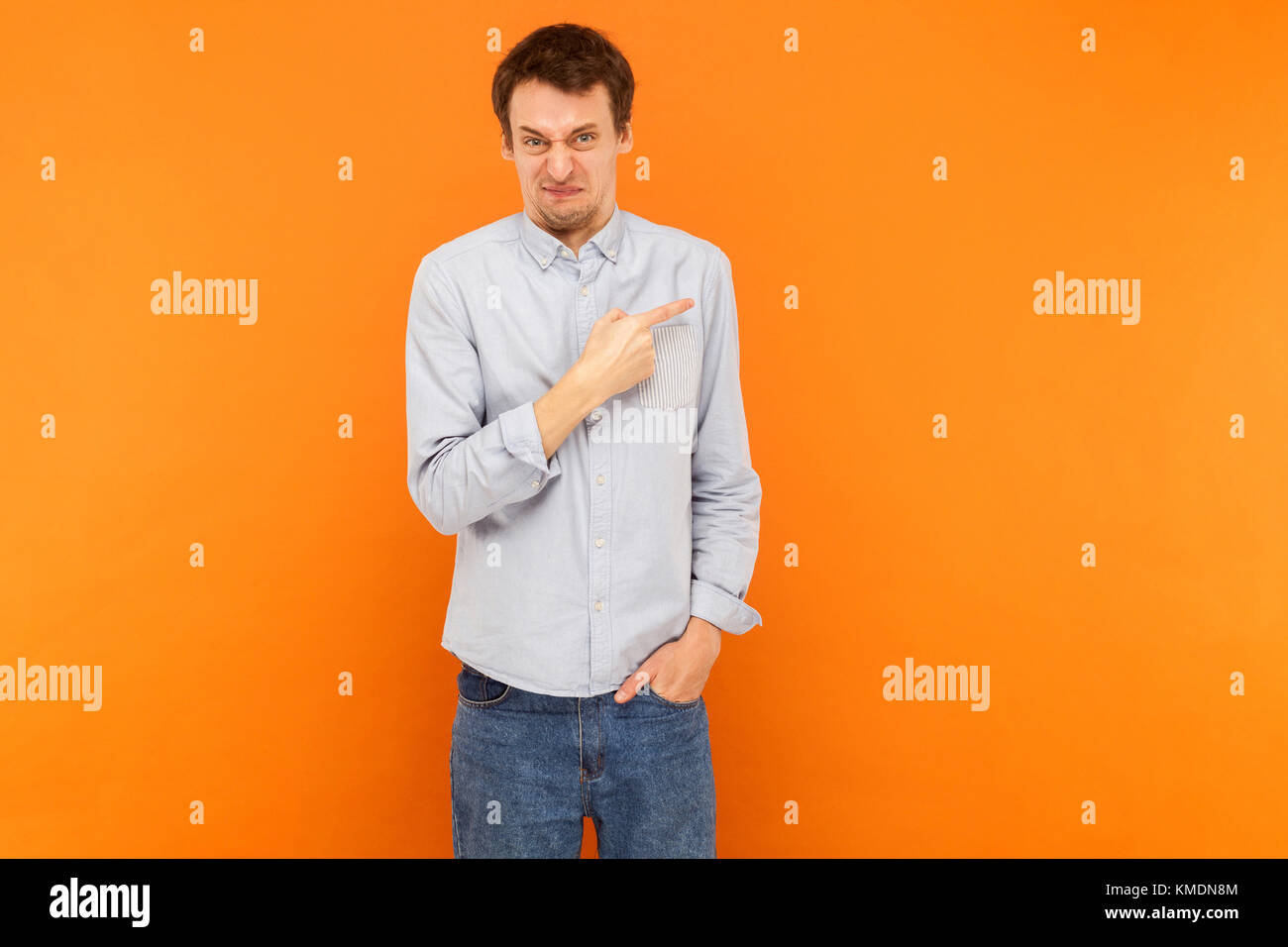 Anger man pointing finger at copy space and looking at camera . Studio ...
