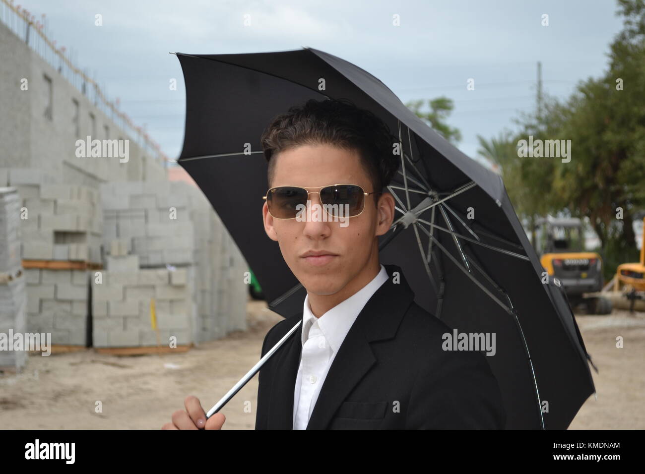 Young man holding umbrella before construction site Stock Photo - Alamy