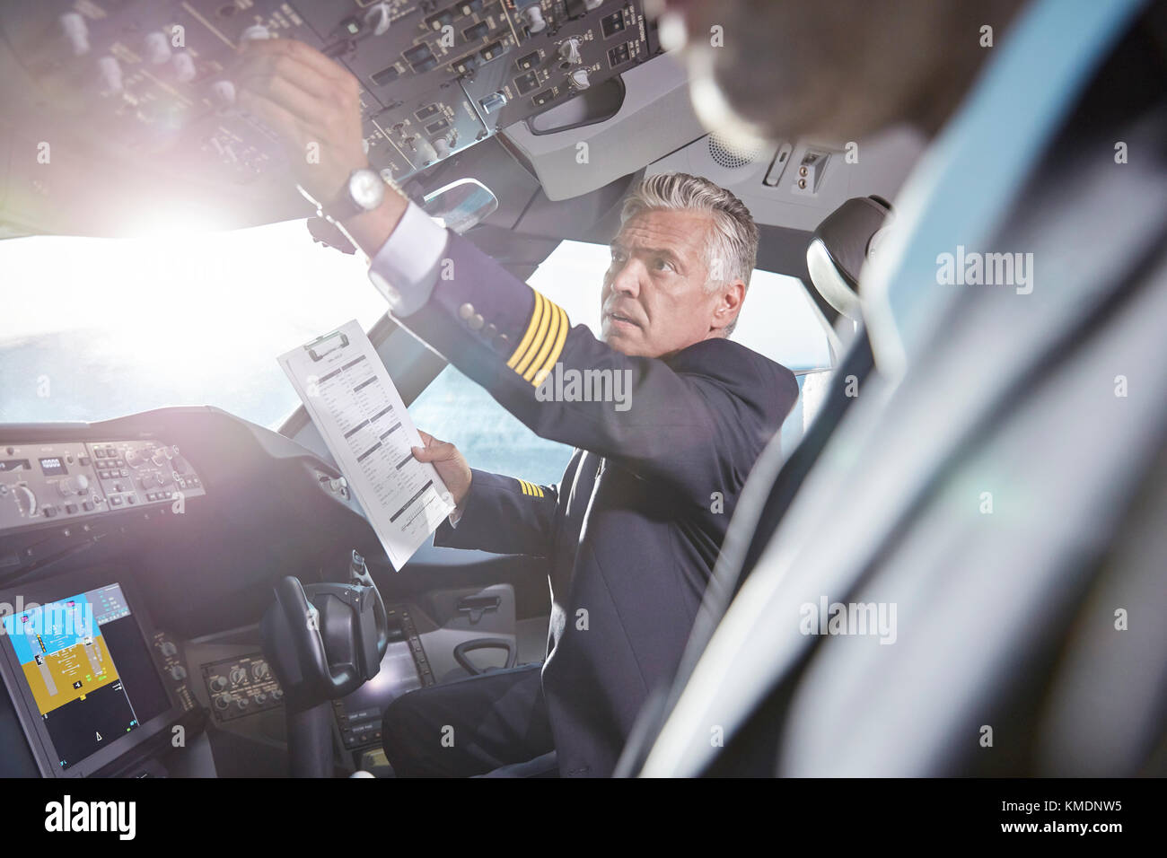 Male pilot with clipboard preparing,adjusting instruments in airplane ...