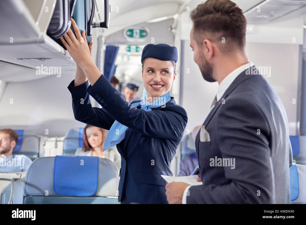 Flight attendant helping businessman with luggage on airplane Stock ...
