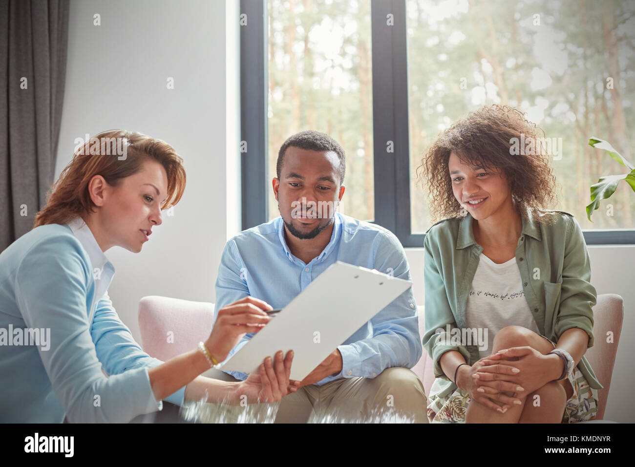 Female therapist with clipboard talking to couple in couples therapy ...