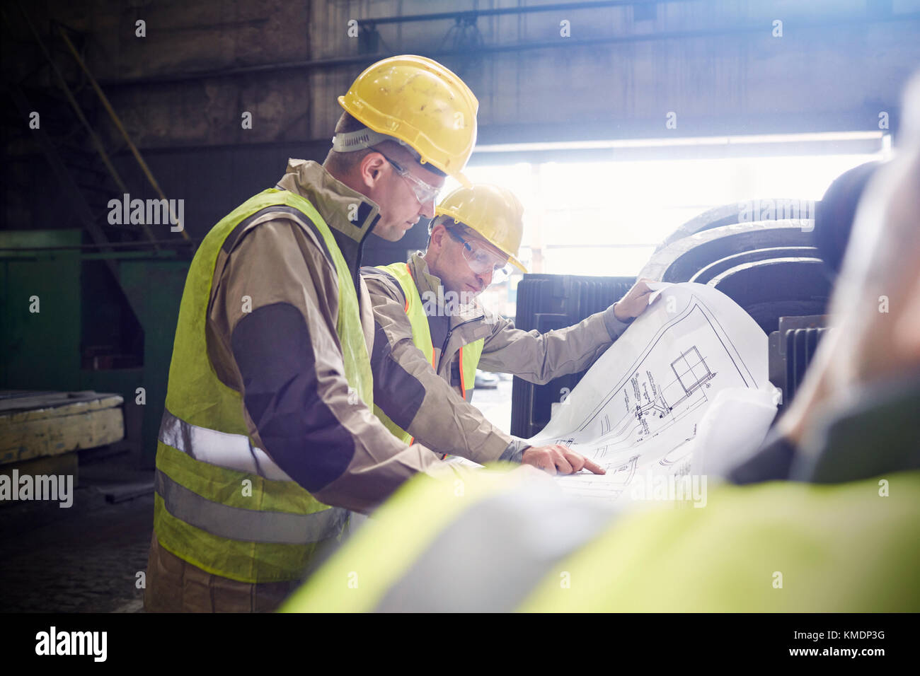 Engineer and steelworker examining blueprints in steel mill Stock Photo ...
