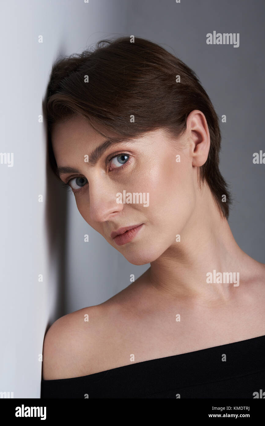 Attractive woman portrait with lean head to wall Stock Photo - Alamy