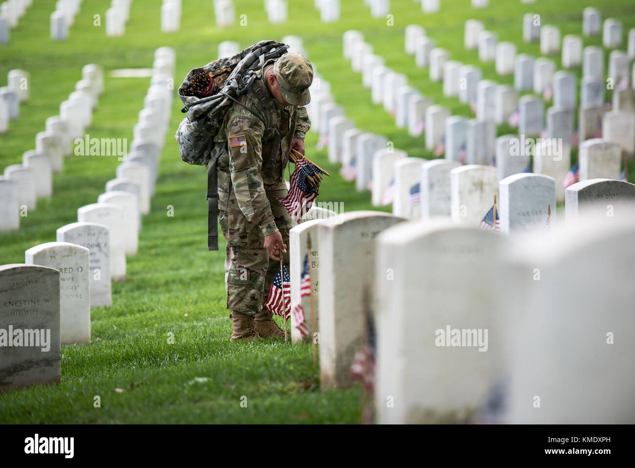 A U.S. Army Old Guard soldier places flags on headstones at the ...