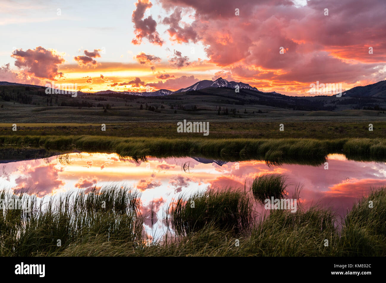 A summer solstice sunset creates red and orange clouds in the sky over ...
