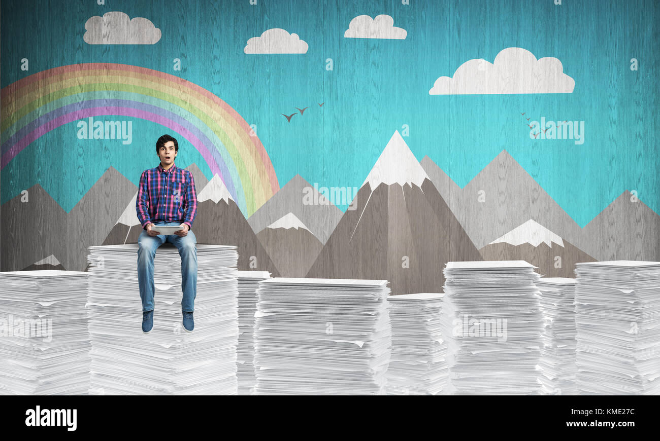 Young man sitting on pile of paper documents Stock Photo - Alamy