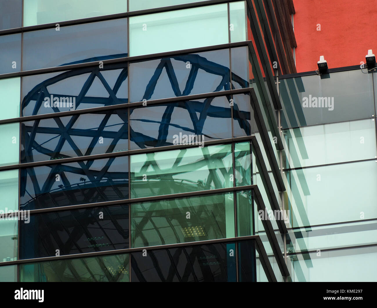 distorted reflections of metallic tower in glazed facade of modern high ...