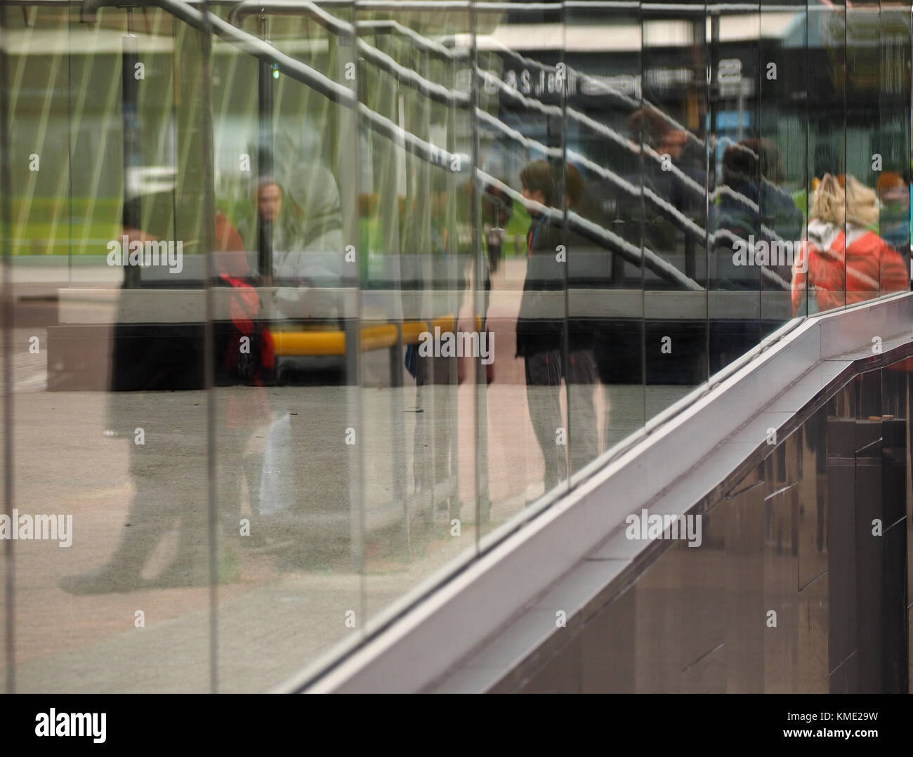 bystanders' distorted reflections in glazed facade of modern high-rise ...