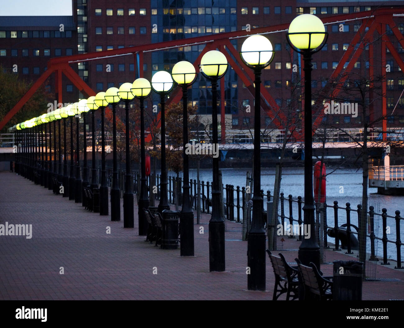 a receding line of globe street lights shining brightly at dusk on the ...