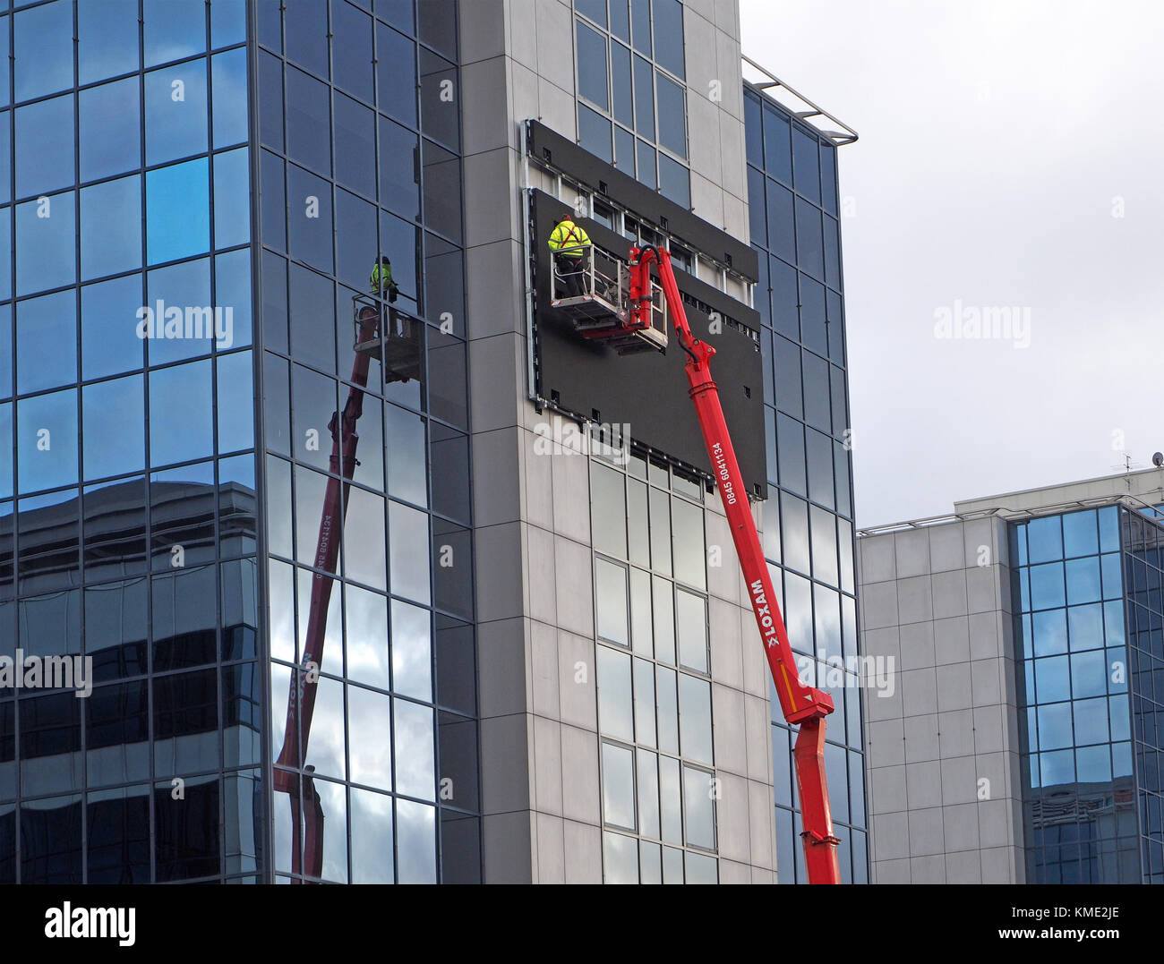 distorted reflections of window cleaner on red cherry picker/crane ...