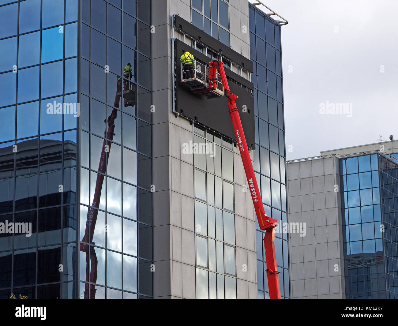 distorted reflections of window cleaner on red cherry picker/crane ...