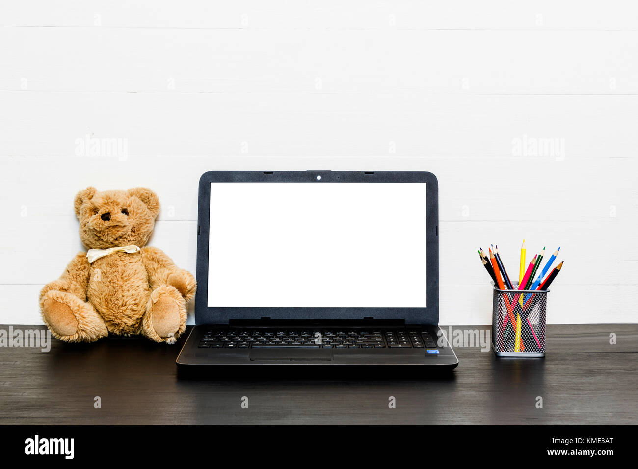 Desk with laptop computer, teddy bear and color pencils. Front view ...