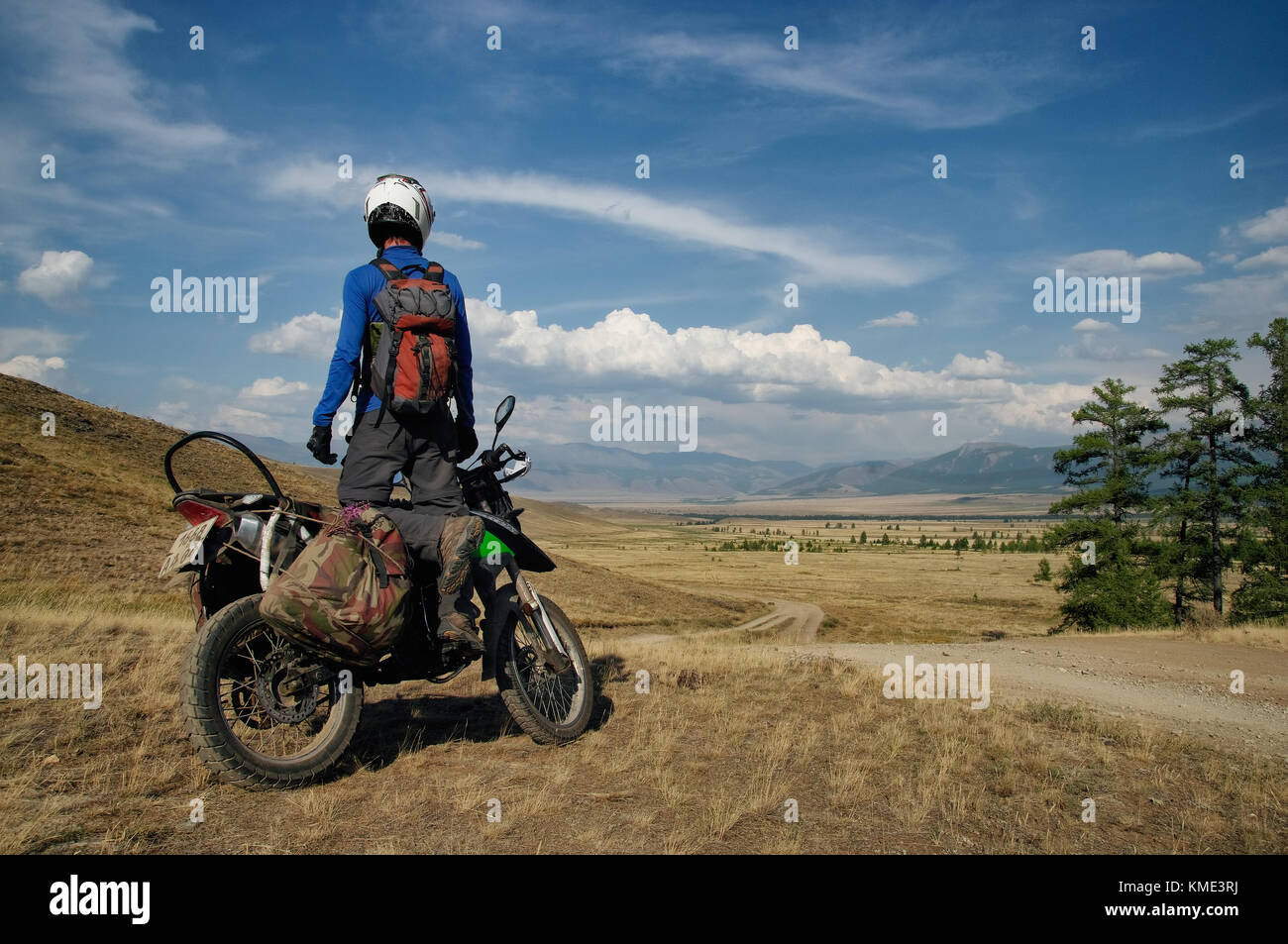 Motorcycle traveler man with suitcases standing on extreme rocky road ...