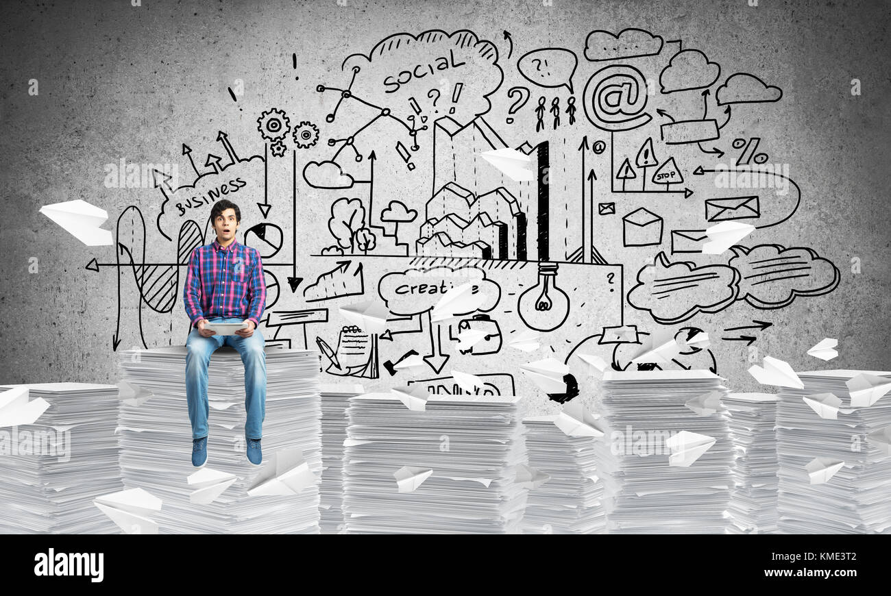 Attractive man sitting on pile of paper documents Stock Photo - Alamy