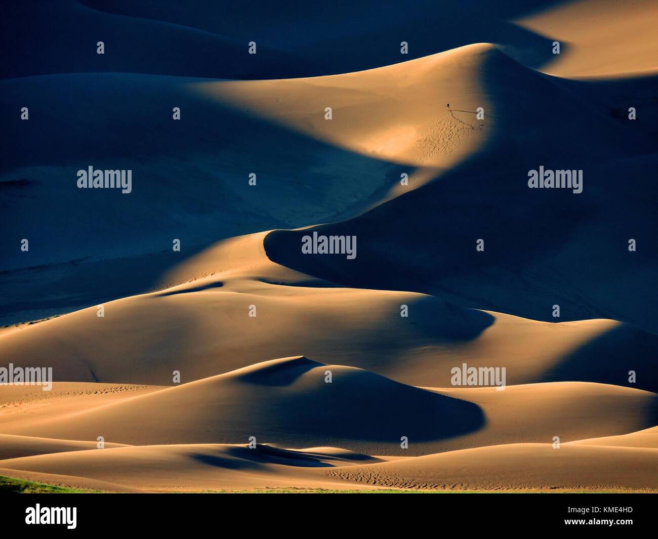 A tourist hikes up the ridge of the Star Dune sand dune at sunset at ...