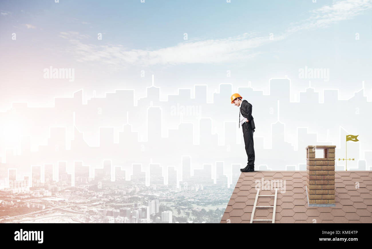 Engineer man standing on roof and looking down. Mixed media Stock Photo ...