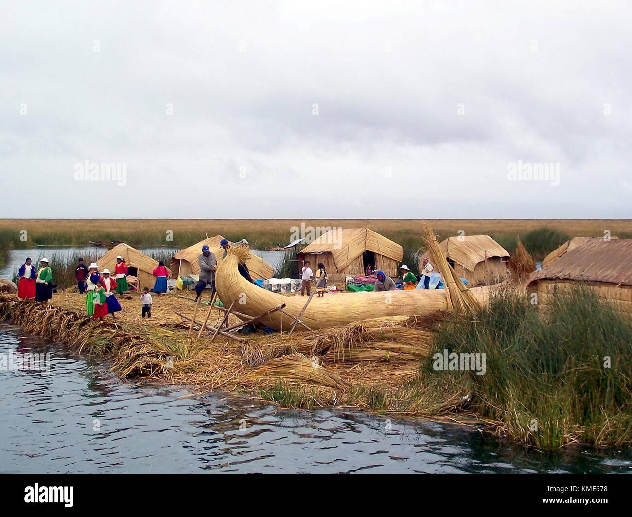 Uros men construct a totora reed boat on a floating reed island on ...