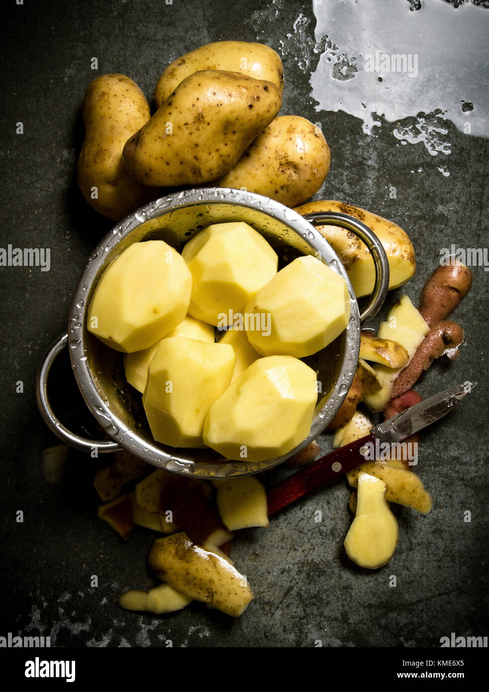 Potato food . The concept of wet peeled potatoes on the stone table ...