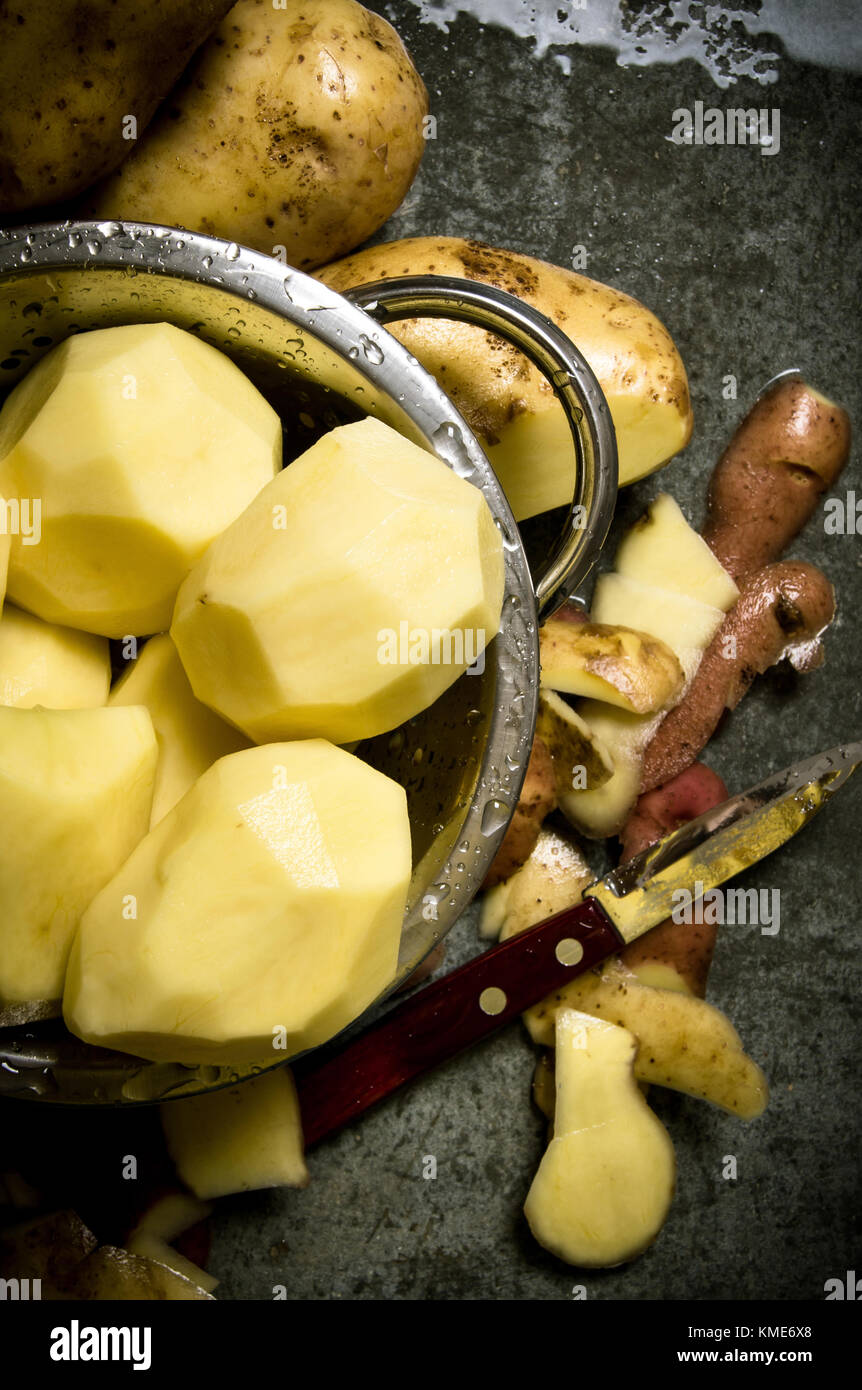 Potato food . The concept of wet peeled potatoes on the stone table ...