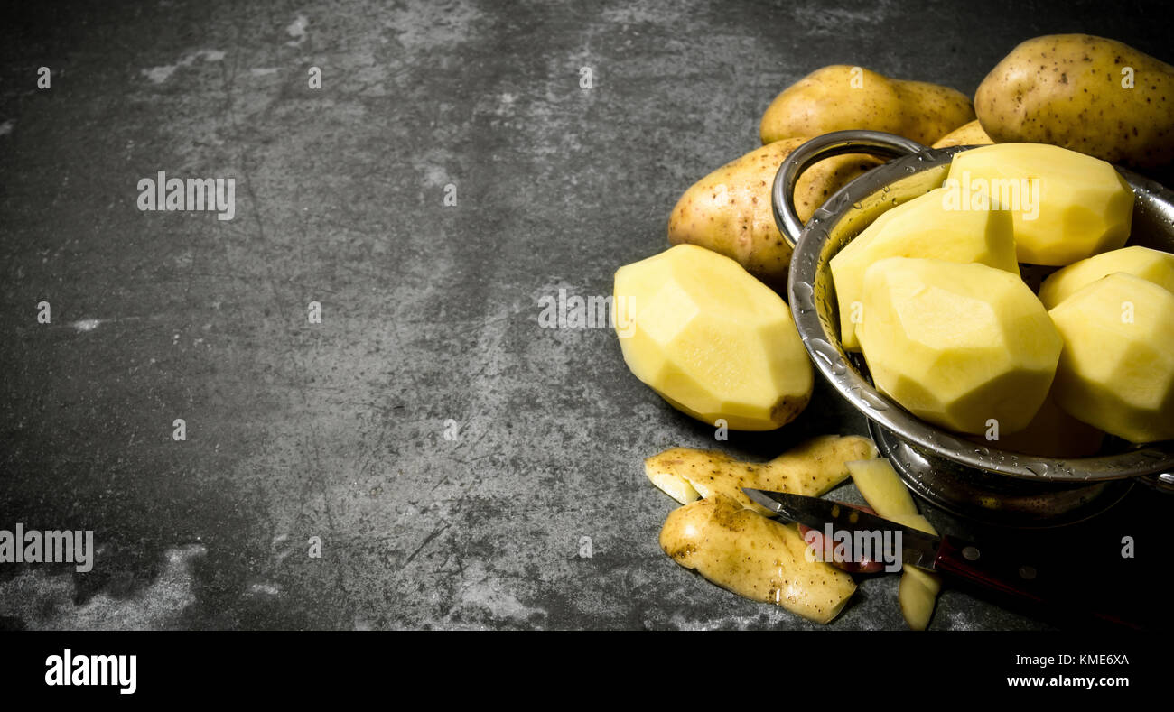 Potato food . The concept of wet peeled potatoes on a stone background ...