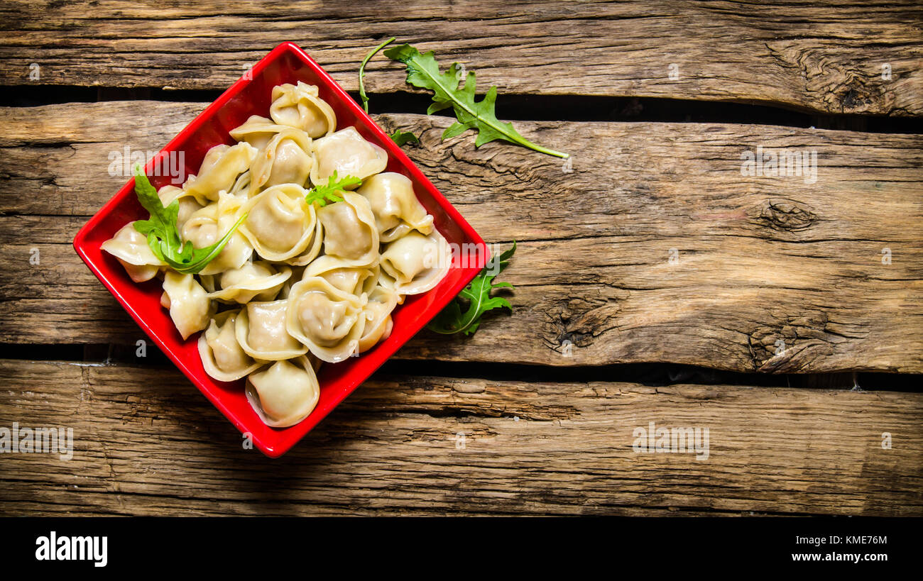 Steamed homemade ravioli with herbs in a Cup. On wooden background ...