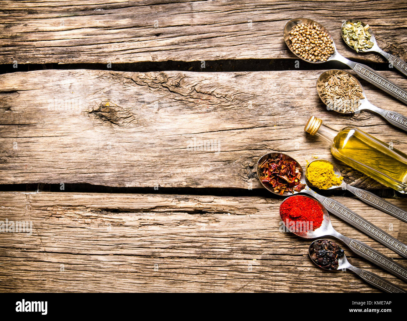 Fragrant spices in spoons with a bottle of olive oil. On wooden ...