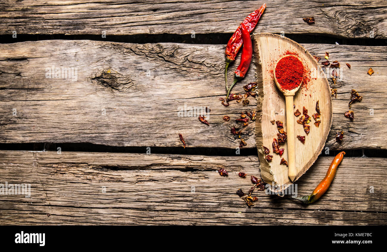 Dried and ground red chili pepper on oak stand. On wooden background ...