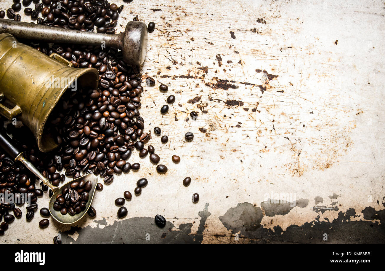 Grain roasted coffee in a mortar with pestle. On rustic background ...