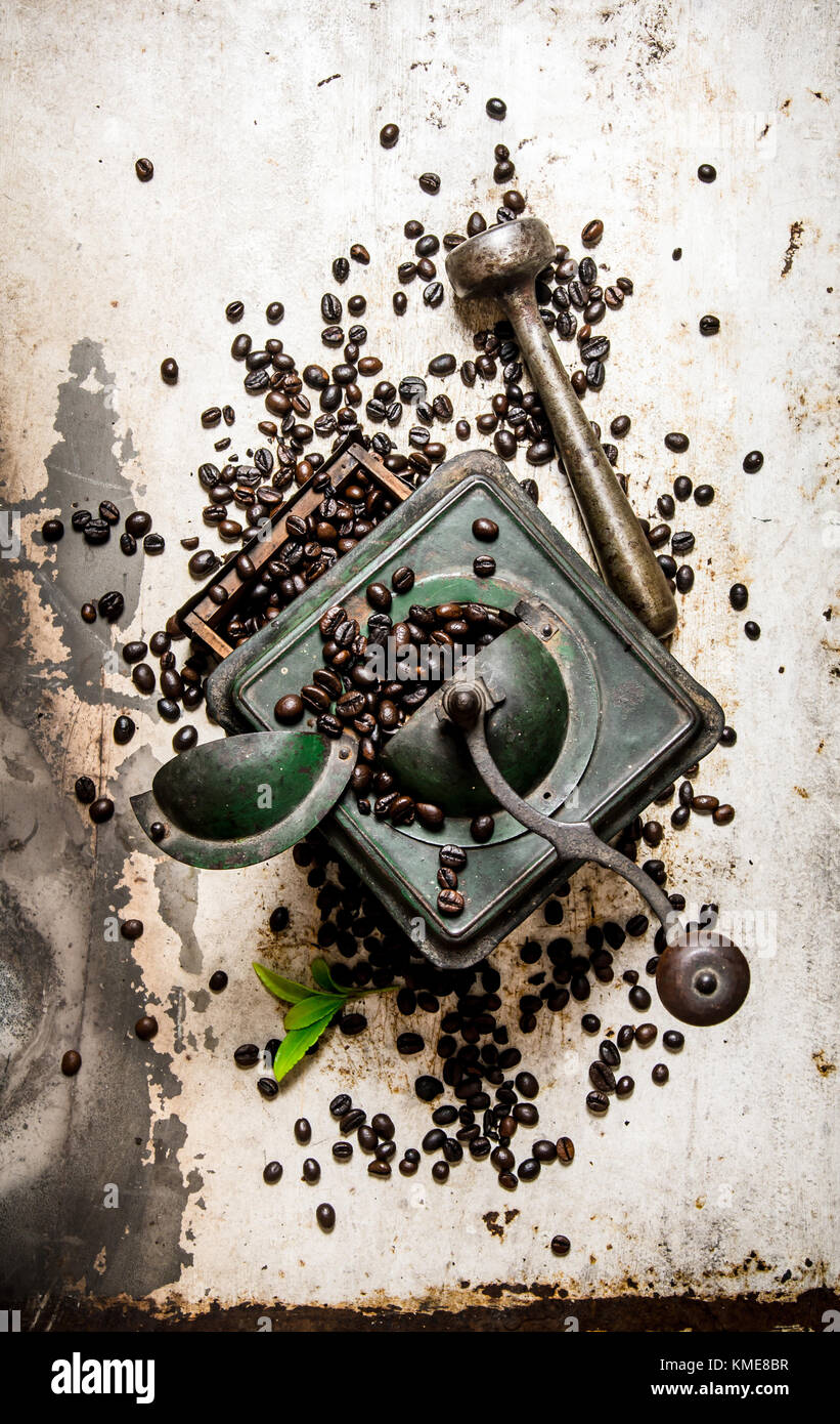 Vintage coffee grinder with pestle and roasted coffee beans. On rustic ...