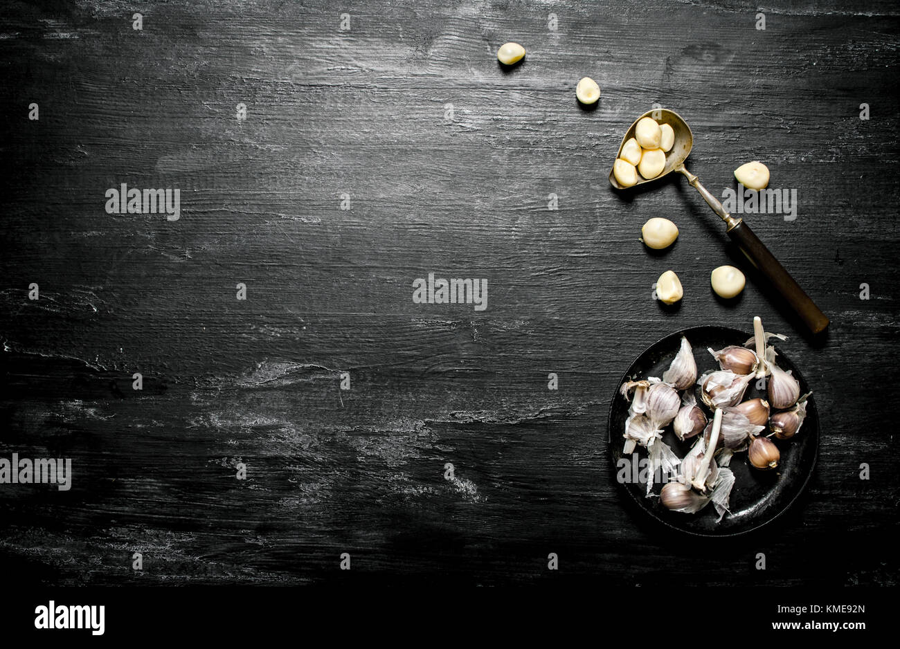 The old garlic in the pan and peeled in a spoon. On black rustic ...