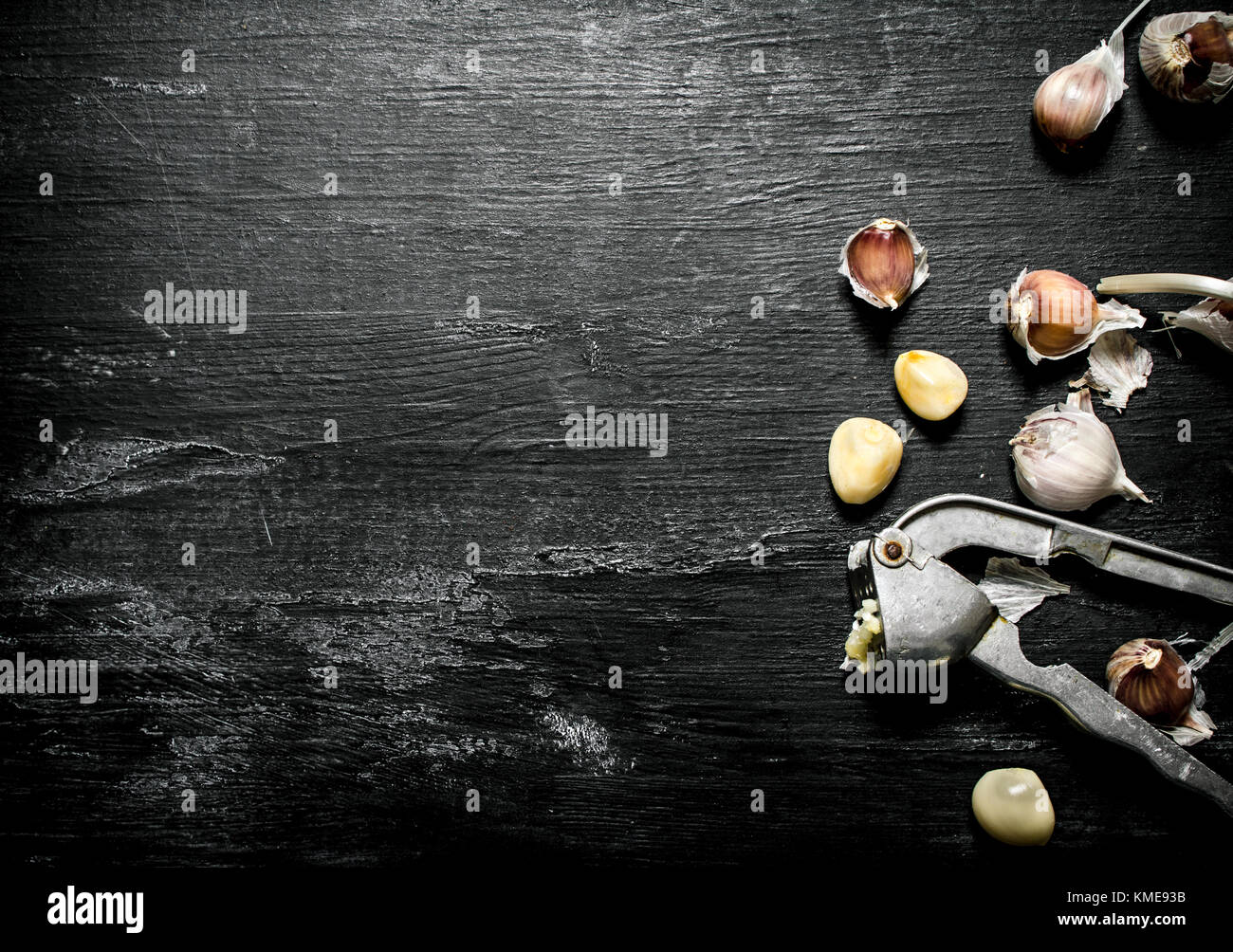 Garlic background. Fresh garlic and garlic press. On black rustic ...