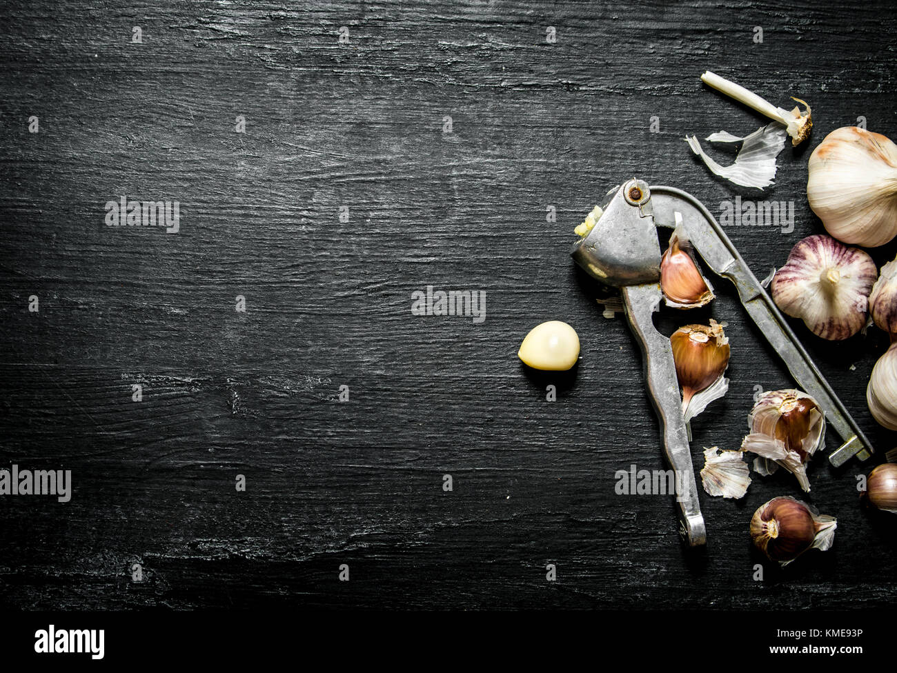 Garlic background. Fresh garlic and garlic press. On black rustic ...
