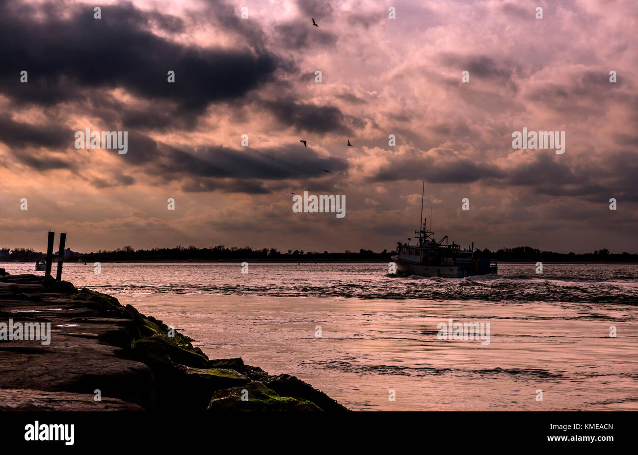 Moody sky with sun rays passing through the clouds over the sea and a ...