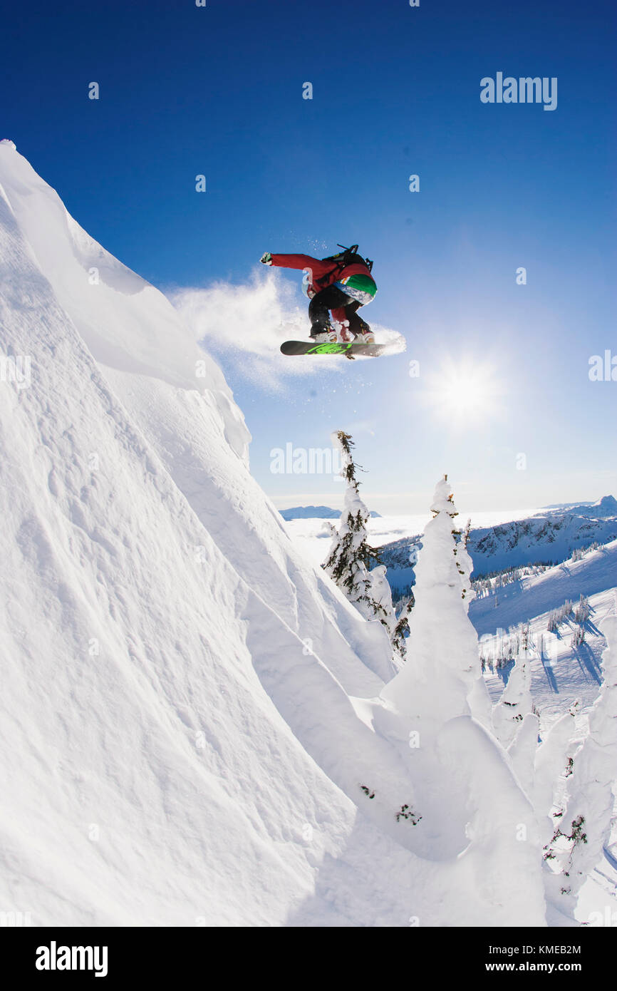 Snowboarder performing a 180 jump while snowboarding,Revelstoke,British ...