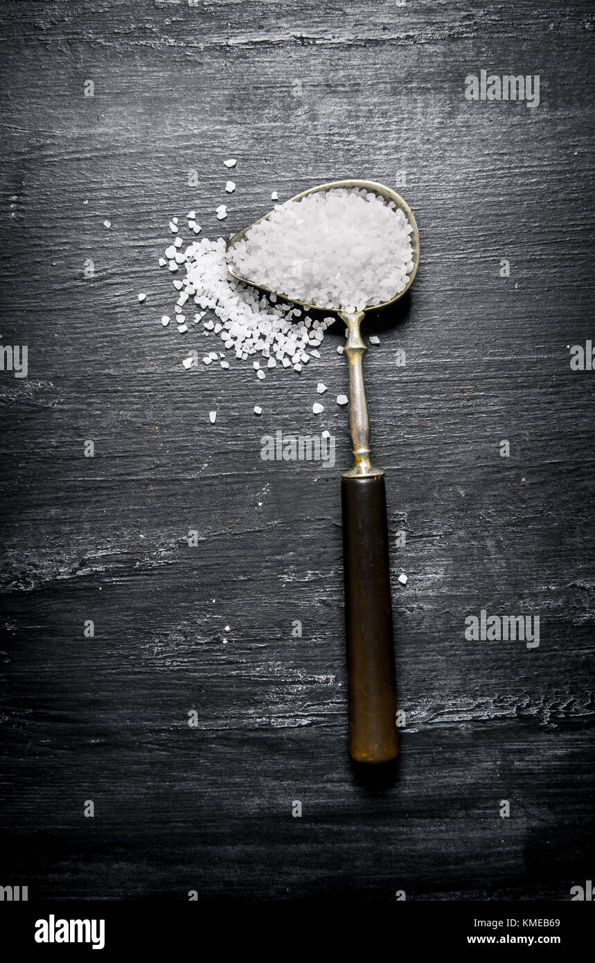 Coarse salt in a large old spoon. On black rustic background Stock ...