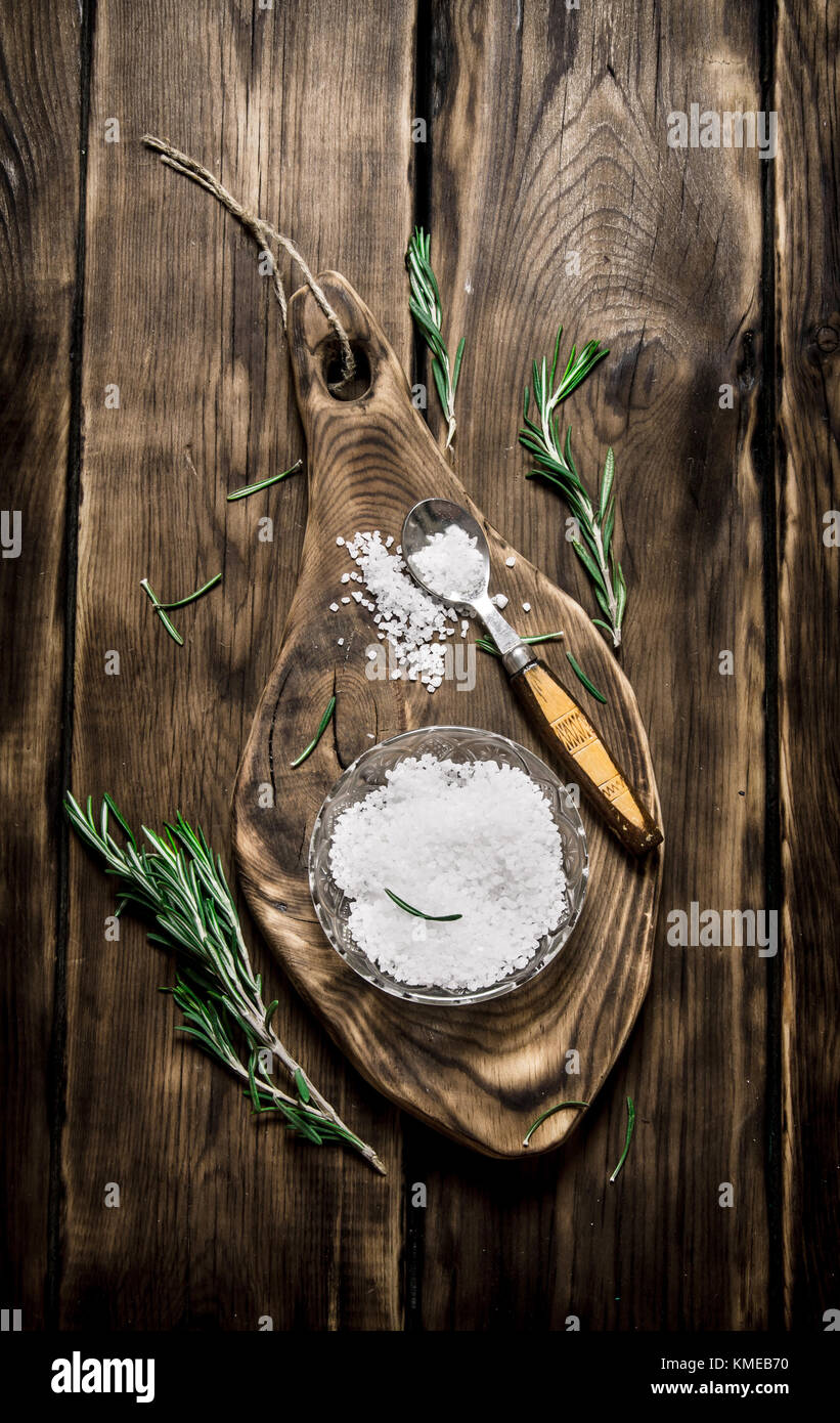 Salt background. Salt with branches of rosemary on the Board. On wooden ...