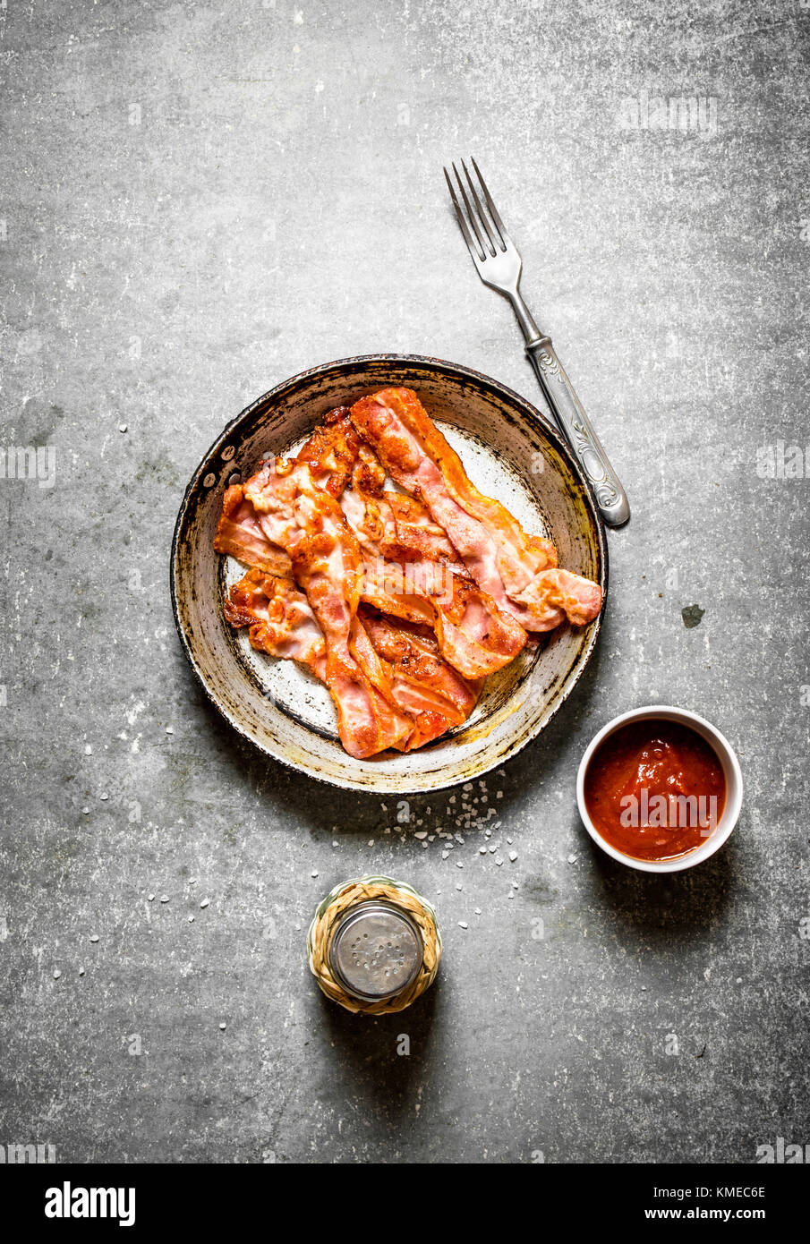 Fried bacon with tomato sauce and salt. On a stone background Stock ...